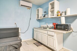Cozinha compacta com armários brancos, micro-ondas e bancada pequena.