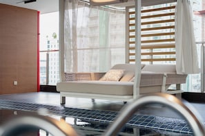 Quarto moderno com cama, janela com persianas e vista para a cidade.