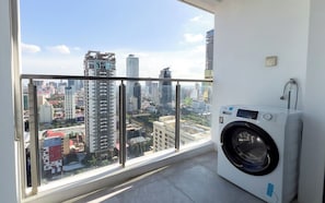 Varanda com vista para a cidade, máquina de lavar e tomada na parede.