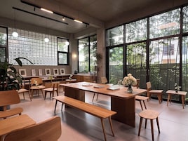 Uma biblioteca moderna com mobiliário de madeira, janelas amplas e plantas em vasos.