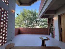 Um espaço ao ar livre moderno com parede de tijolos, uma mesa de madeira com um livro e vista para árvores.