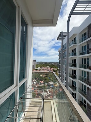 Um edifício alto com varanda de vidro e vista para uma área residencial.