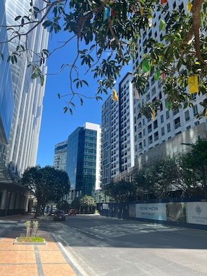 Rua urbana com edifícios modernos, céu claro e uma placa indicando Positano Mactan.