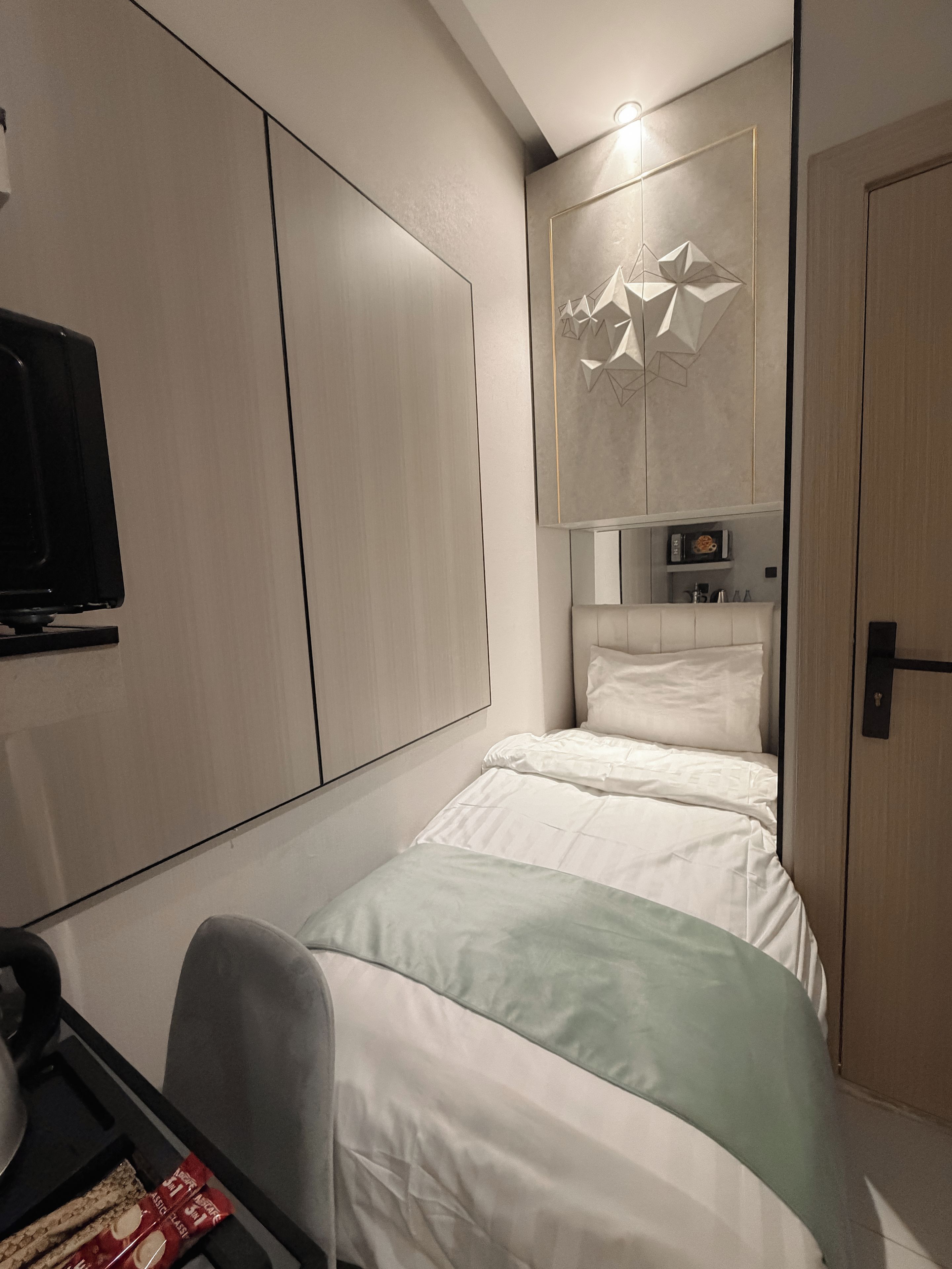 Quarto com cama, escrivaninha, cadeira, televisão e guarda-roupa.