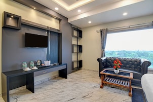 Uma sala de estar moderna com televisão de tela plana, um sofá, uma mesa de centro e vista para o exterior.