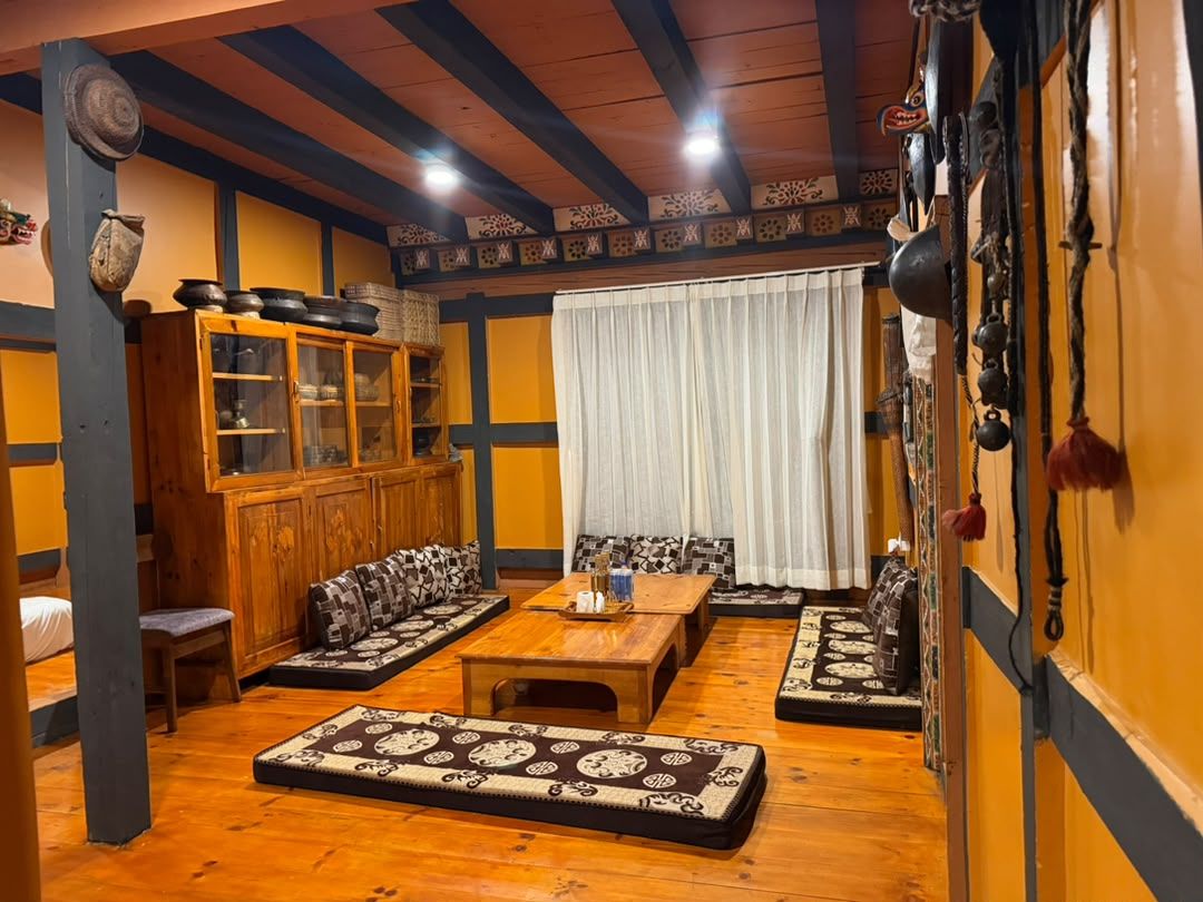 Quarto tradicional com piso de madeira, mesa de jantar, sofás e um armário.
