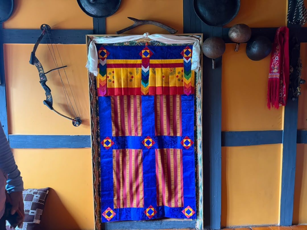 Um quarto com um edredom colorido pendurado na parede, um laço e um lenço vermelho.
