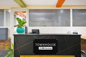 Uma mesa de recepção com uma placa que diz 'TOWNHOUSE' e 'YOY-Serviced'.