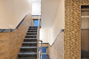 Uma escada moderna com corrimão de metal que leva a uma porta azul.