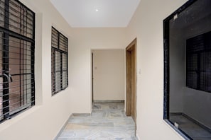Corredor com piso de azulejos, porta de madeira e janelas com grades.