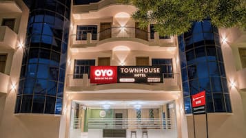 Um hotel com vários andares, com destaque para a placa 'OYO Townhouse Hotel' e a funcionalidade 'Reserve no Aplicativo'.
