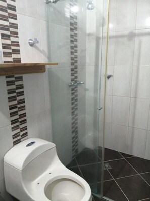 Um banheiro moderno com box de vidro, vaso sanitário branco e piso cerâmico.