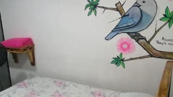 Quarto com uma cama, um mural de um pássaro na parede e um almofada rosa em uma cadeira.