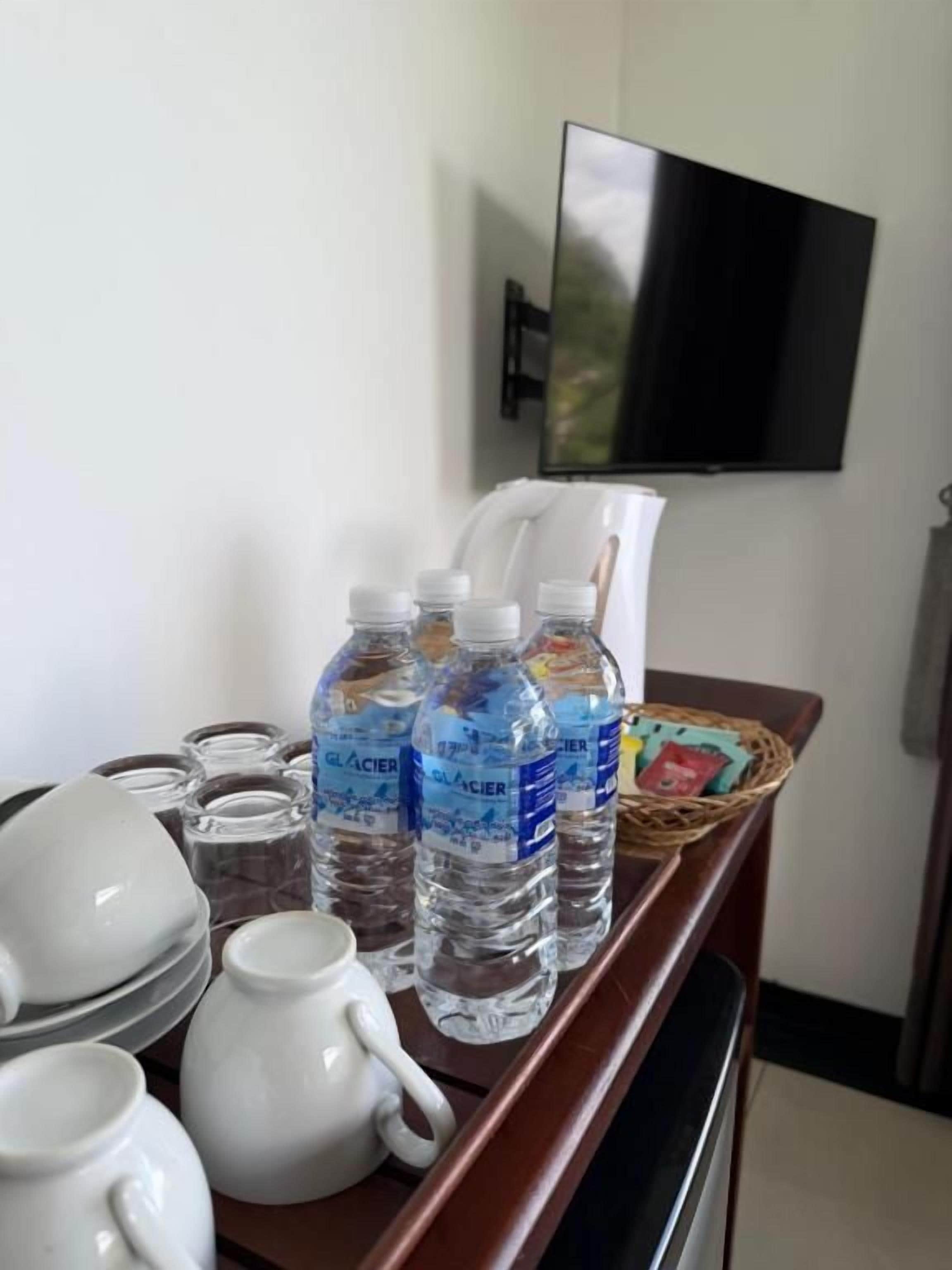 Uma mesa com garrafas de água, um jarro branco e uma cesta com objetos.