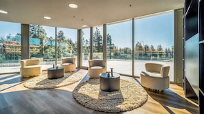 Sala de estar moderna com amplas janelas, televisão de tela plana e vista para a paisagem urbana.