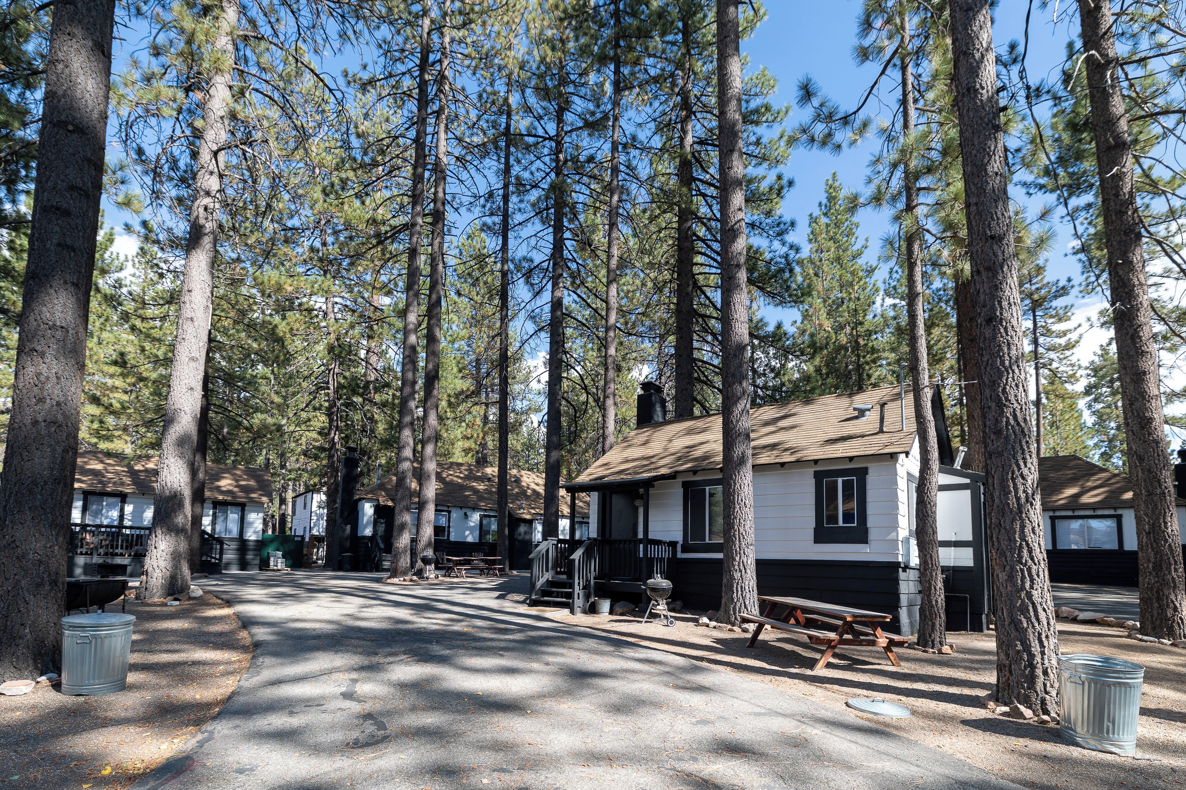 Um parque de campismo com várias cabanas, mesas de piquenique e um céu limpo.