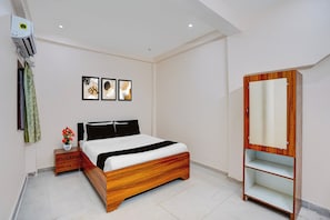Quarto com cama de madeira, mesa de cabeceira, ar condicionado fixado na parede e guarda-roupa de madeira com espelho.