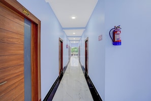 Corredor de hotel com portas de madeira, um extintor preso na parede e uma placa indicando a suíte 207.