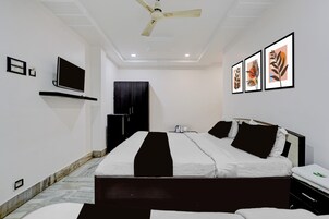 Quarto de hotel com cama, TV de tela plana, ventilador de teto e obras de arte na parede.