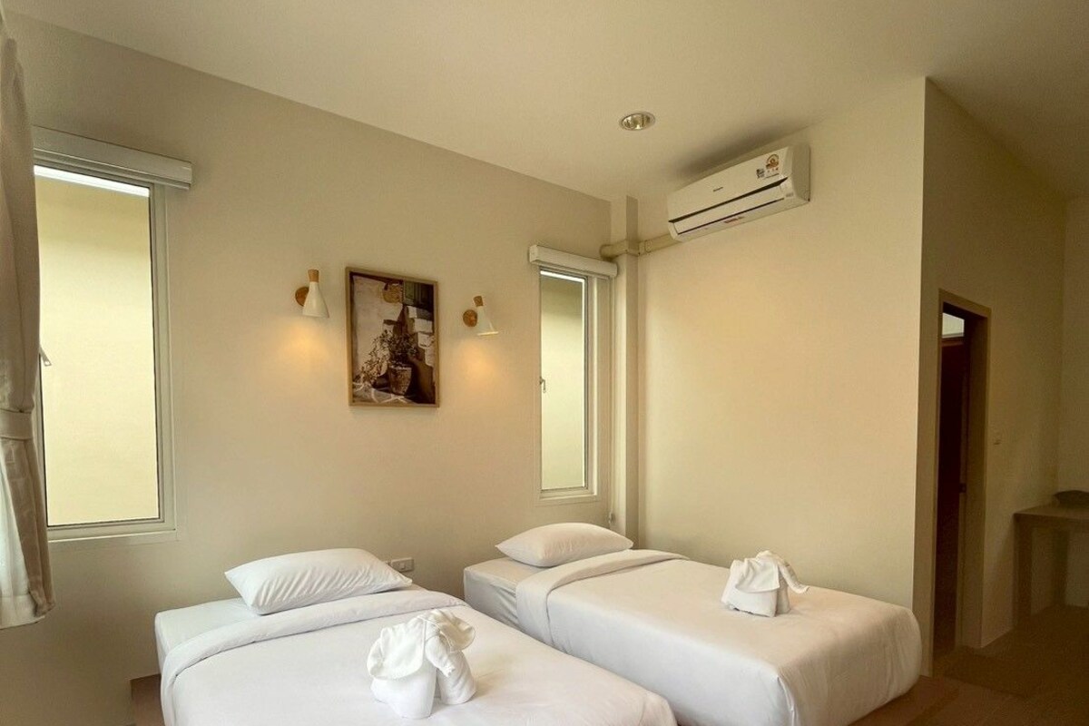 Quarto de hotel com duas camas, um quadro na parede, ar condicionado e uma janela com cortinas.
