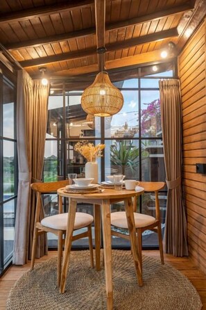 Uma área de refeições com uma mesa redonda, cadeiras e um lustre.