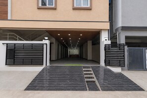 Fachada moderna de um edifício com acesso coberto, escadas e portão.