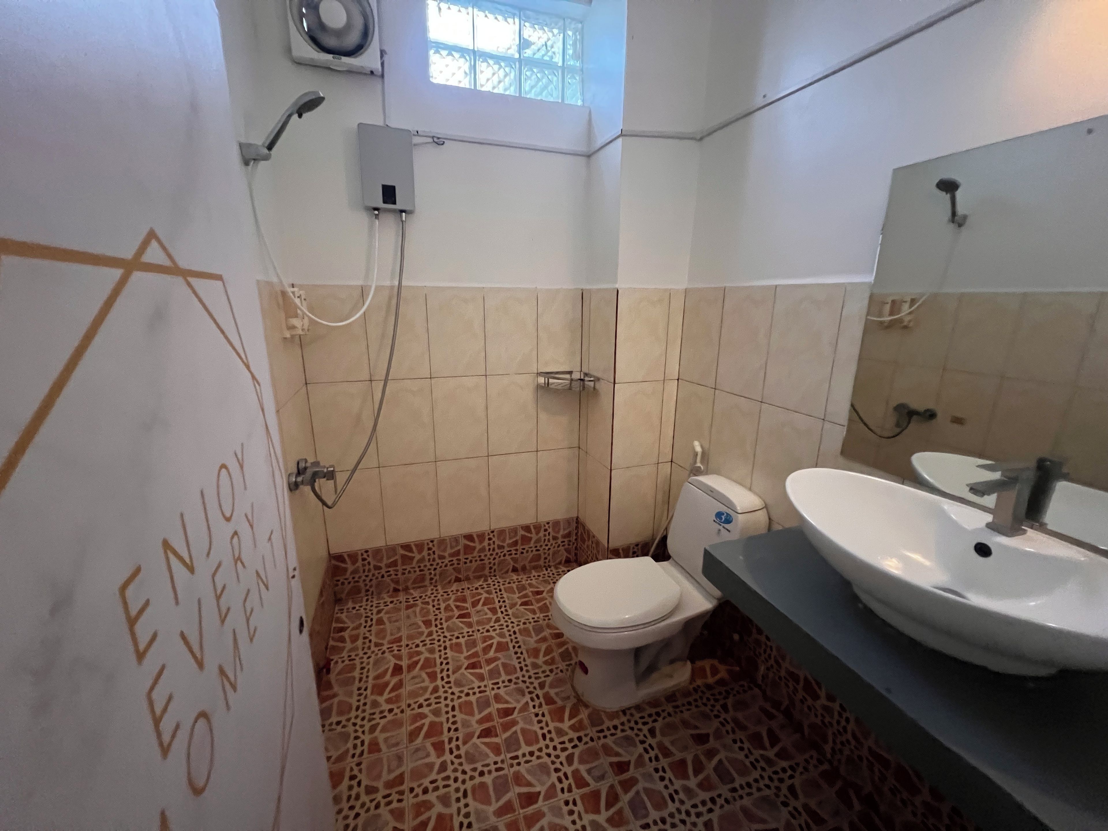 Casa de banho com sanita, lavatório e chuveiro.