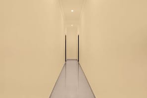 Um corredor estreito, bem iluminado, com piso liso e paredes simples.