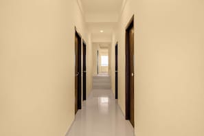 Um corredor com portas em ambos os lados, dando acesso a uma escadaria.