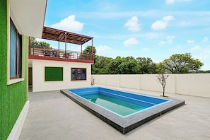 Uma casa moderna de dois andares, com piscina, varanda e vista para árvores.