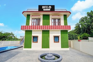 Hotel com placa, duas janelas, piscina e fonte.