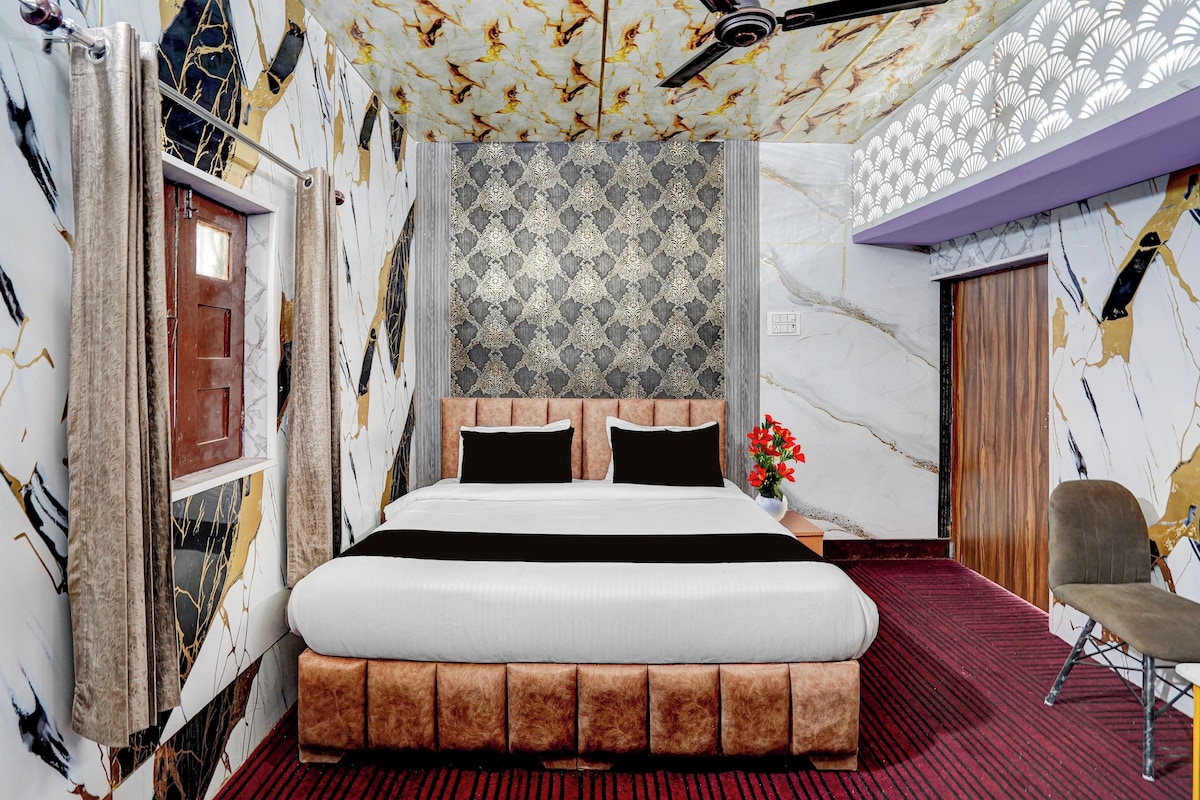 Quarto com uma cama grande, porta de madeira e papel de parede estampado.