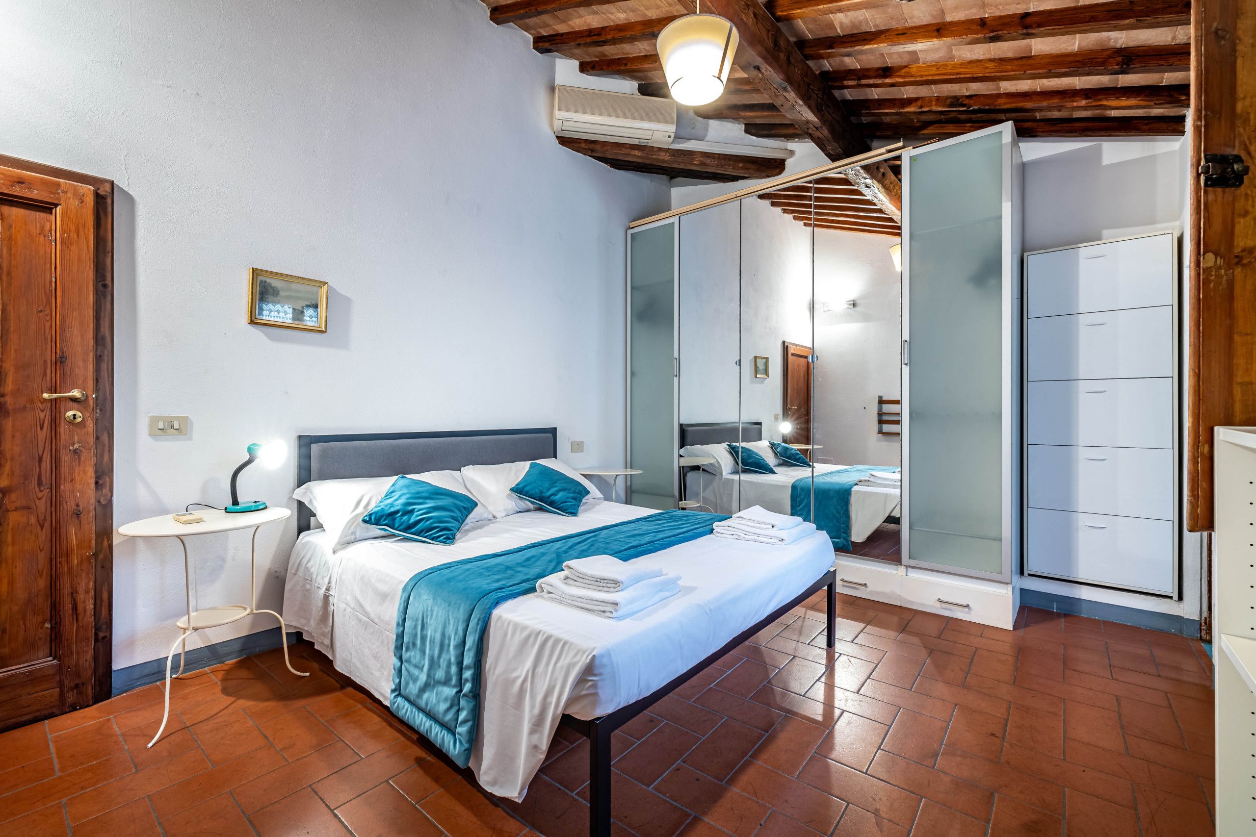 Quarto com cama, mesa de cabeceira e guarda-roupa.