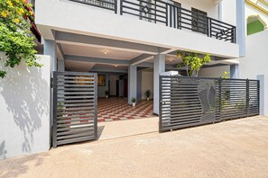 Um edifício moderno de dois andares com portão fechado, piso xadrez e plantas em vasos.