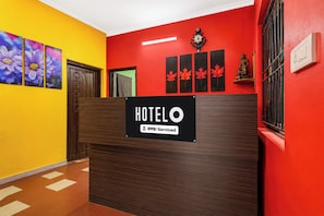 Balcão de recepção de hotel com uma placa indicando que o serviço é realizado pela OYO.