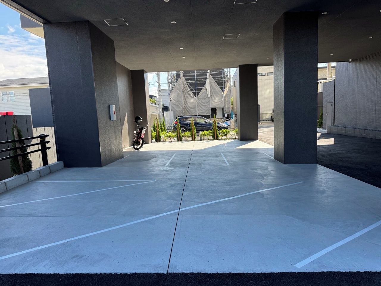 Uma área de estacionamento com piso de concreto e uma motocicleta ao fundo.
