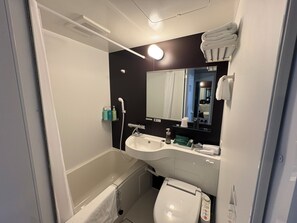 Casa de banho compacta com sanita, lavatório e chuveiro.