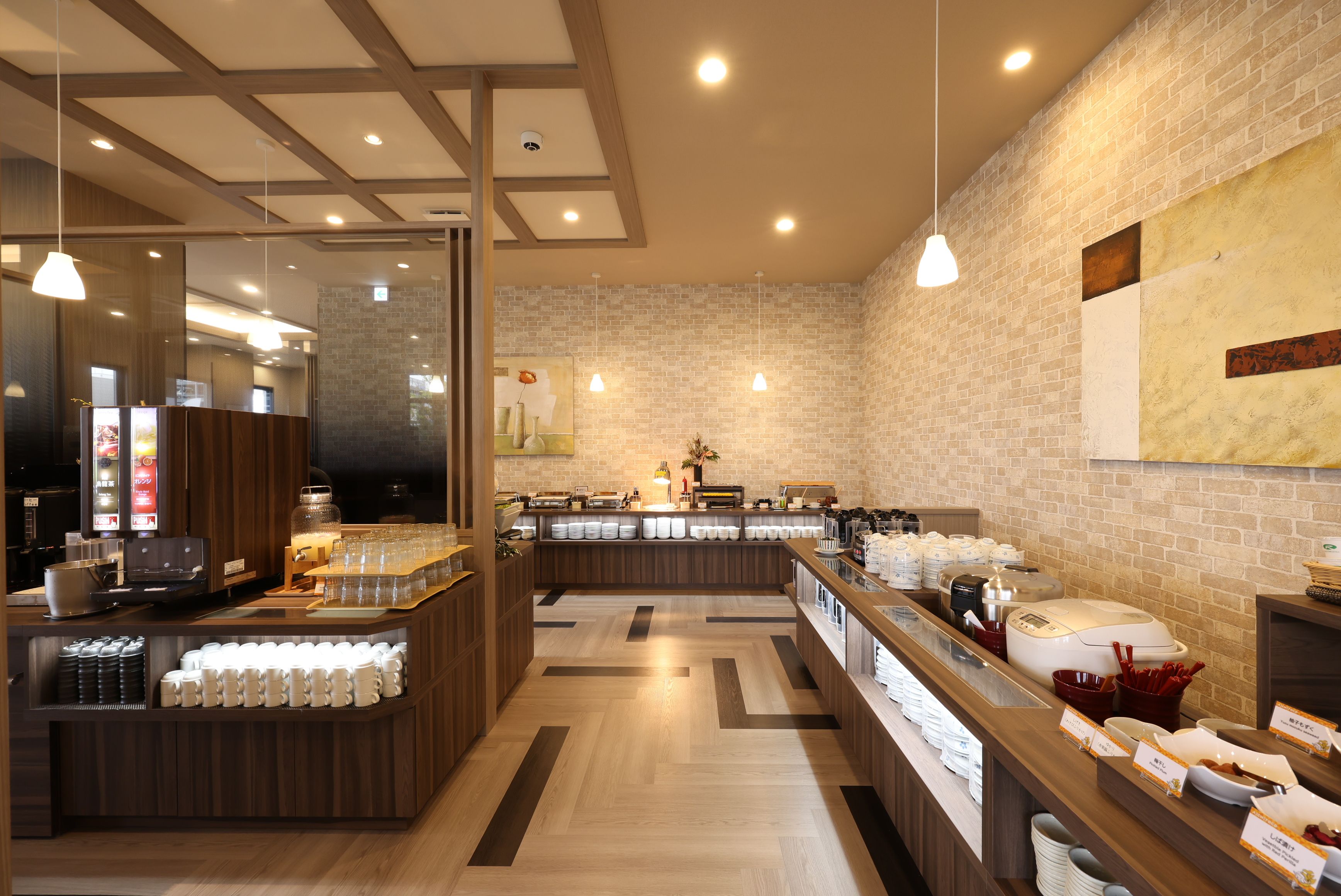 Um buffet de café da manhã moderno com parede de tijolos, balcões de madeira e diversas opções de comida e bebida.