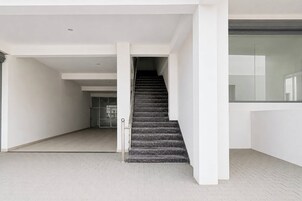 Um interior moderno com escada que leva a um nível inferior, paredes brancas e piso de azulejos.