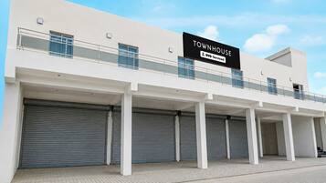 Uma casa geminada moderna com um grande anúncio de Oyo-Serviced. Apresenta fachada plana, várias portas de garagem e uma varanda com grades de metal.