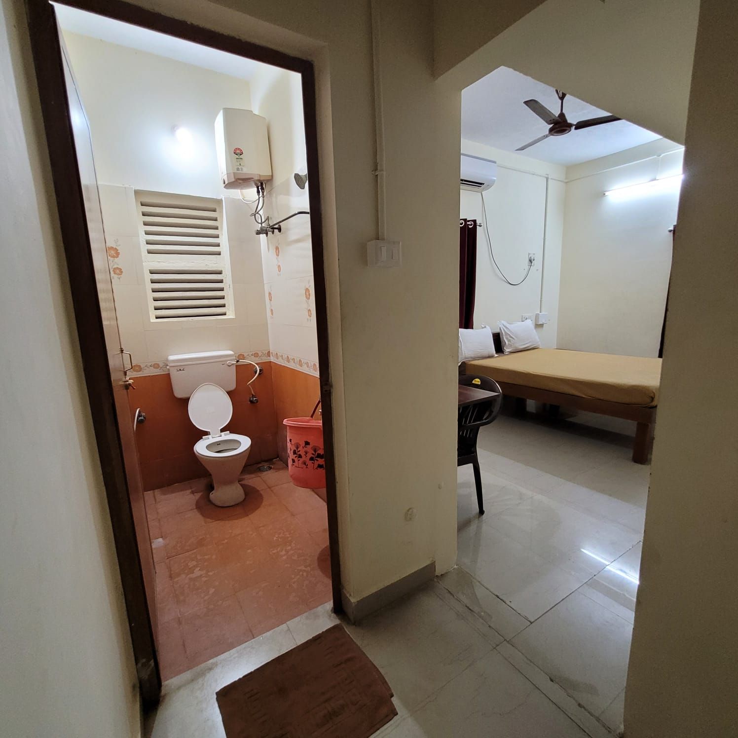 Casa de banho com sanita, chuveiro e cama na divisão adjacente.