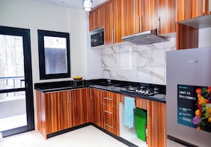 Cozinha moderna com armários de madeira, bancada preta, micro-ondas e fogão a gás.