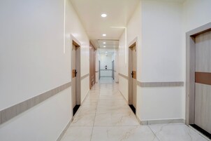 Um corredor com portas em ambos os lados, piso ladrilhado e iluminação embutida no teto.
