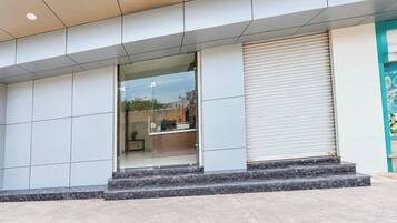 Um edifício moderno com entrada de vidro, porta com persiana fechada e fachada revestida de azulejos.