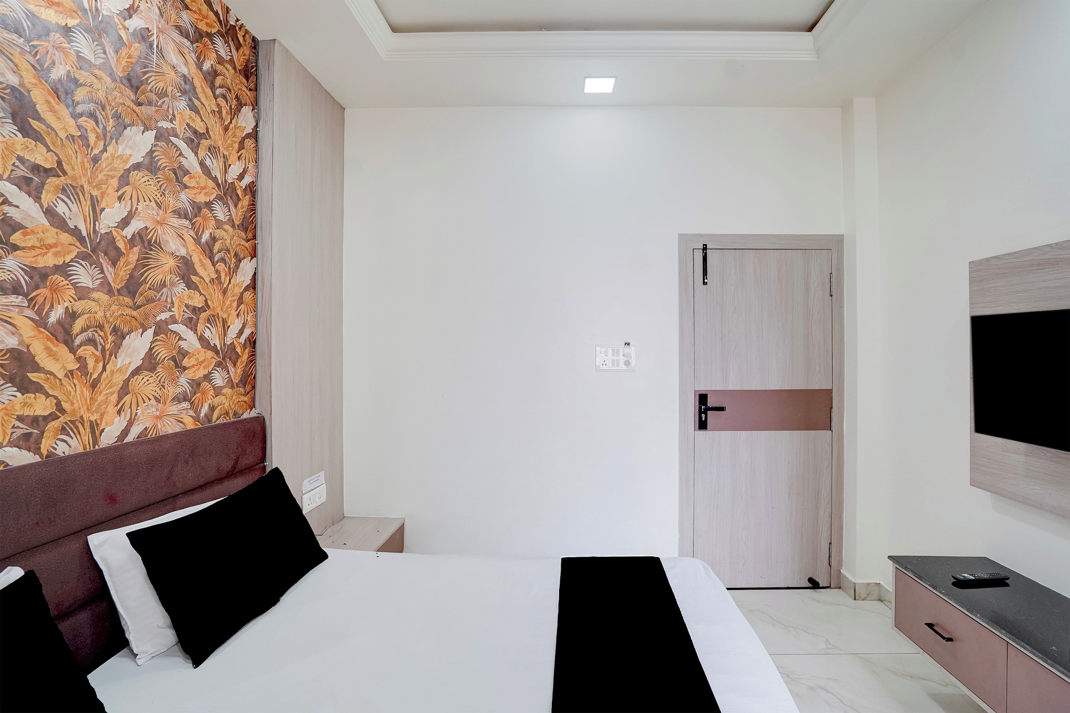 Quarto de hotel com cama, televisão, guarda-roupa e porta.