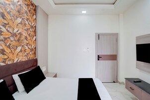 Quarto de hotel com cama, televisão, guarda-roupa e porta.
