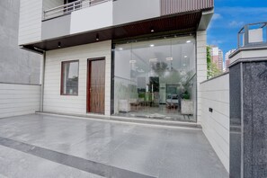 Um edifício moderno com entrada de vidro, porta de madeira e varanda.