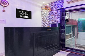 Balcão de recepção com a placa 'Collection', uma parede de pedra e área de recepção.
