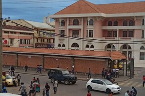 Cena de rua com um edifício de telhado vermelho e janelas em arco.