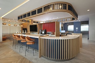 Cozinha moderna com ilha curva, banquetas e eletrodomésticos embutidos.